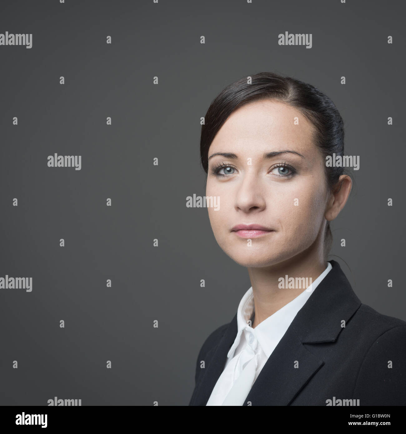 Confident young female manager smiling at camera, posing on gray ...