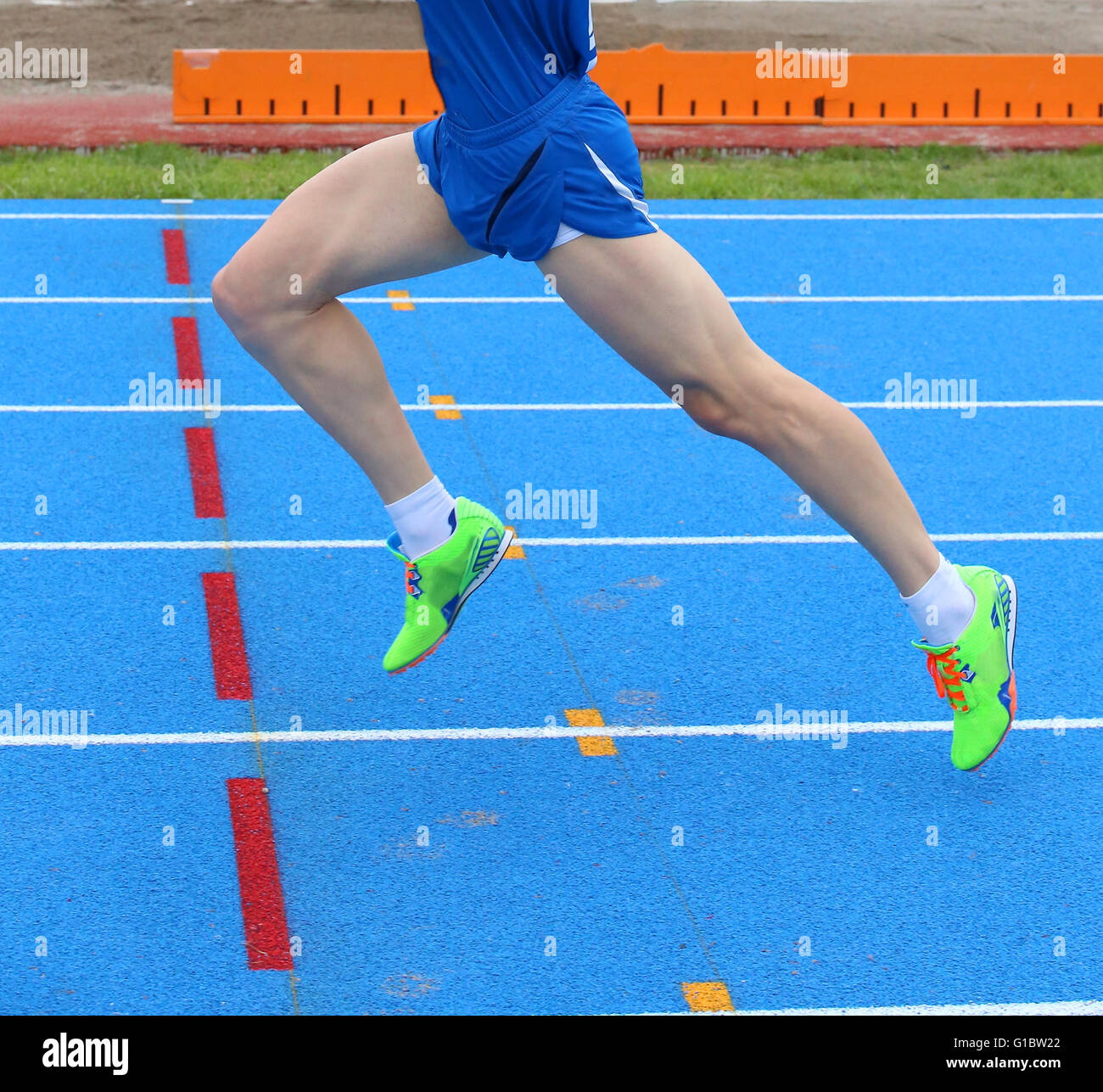 long legs of fast runner runs into the blue in athletics track Stock ...