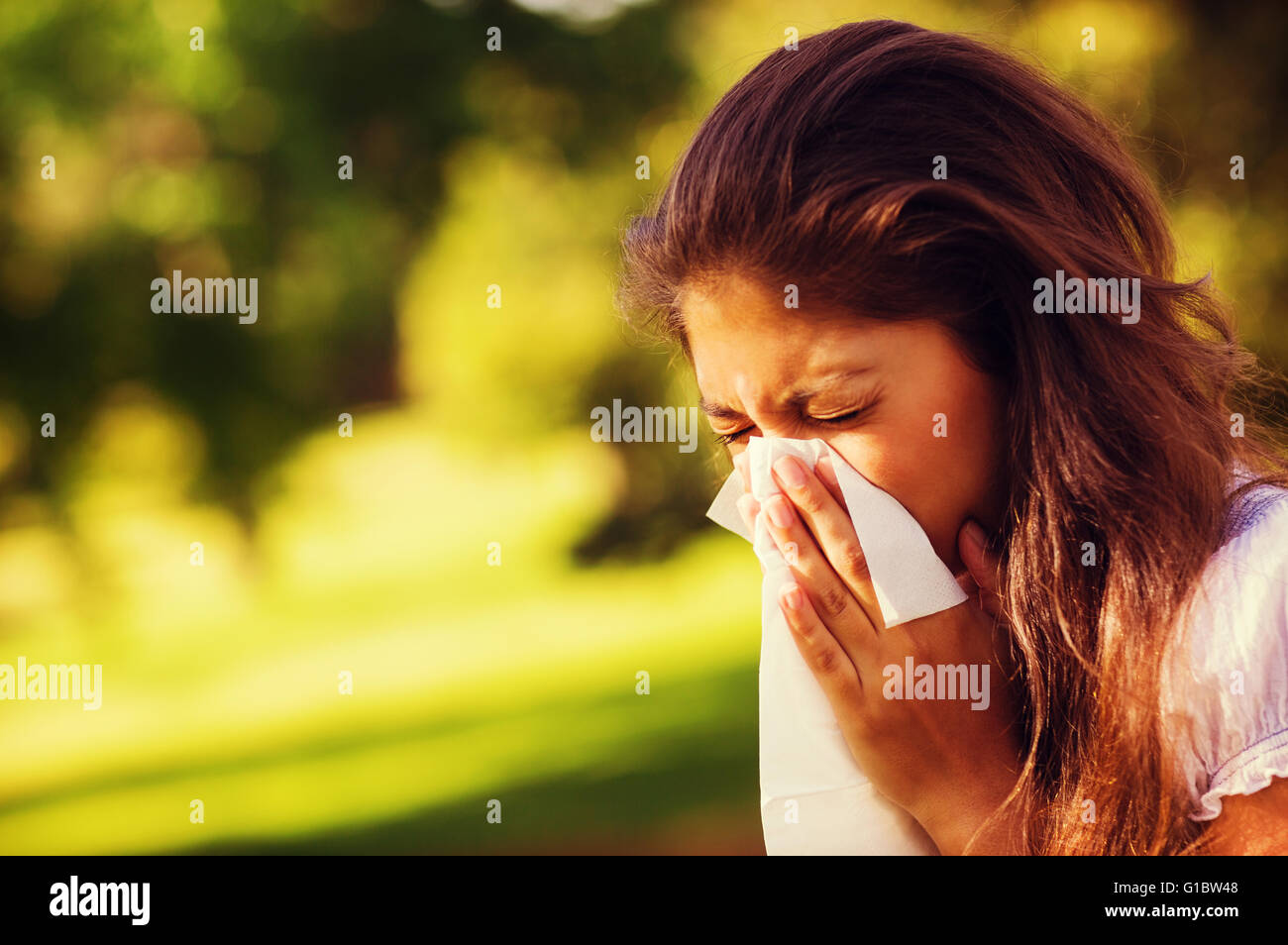 Woman blowing nose with tissue paper at park Stock Photo - Alamy