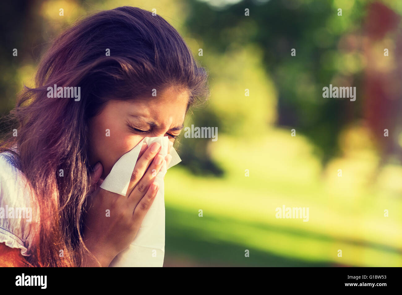 Woman blowing nose with tissue paper at park Stock Photo - Alamy