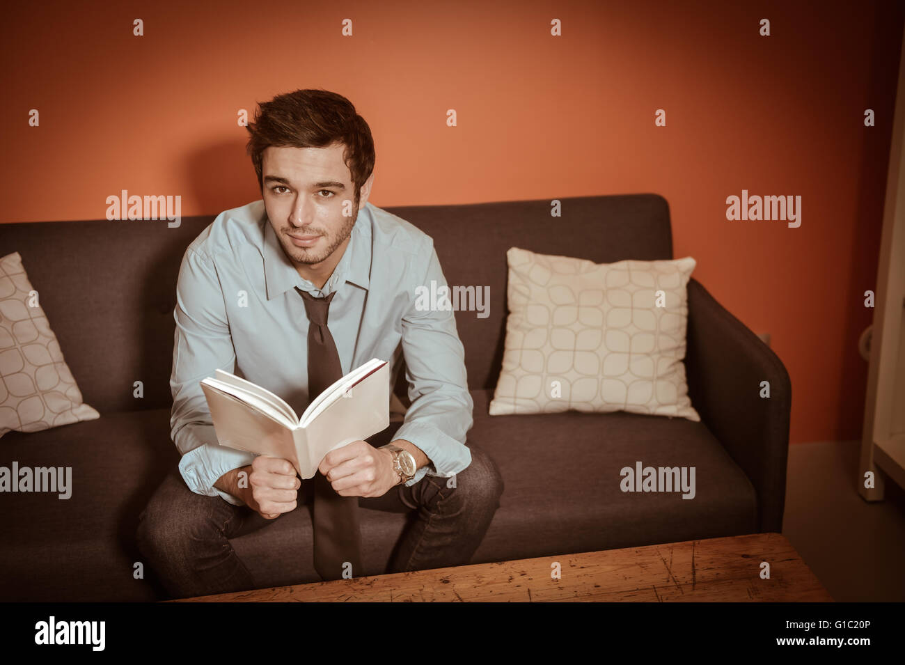 Man at home reading book Stock Photo - Alamy
