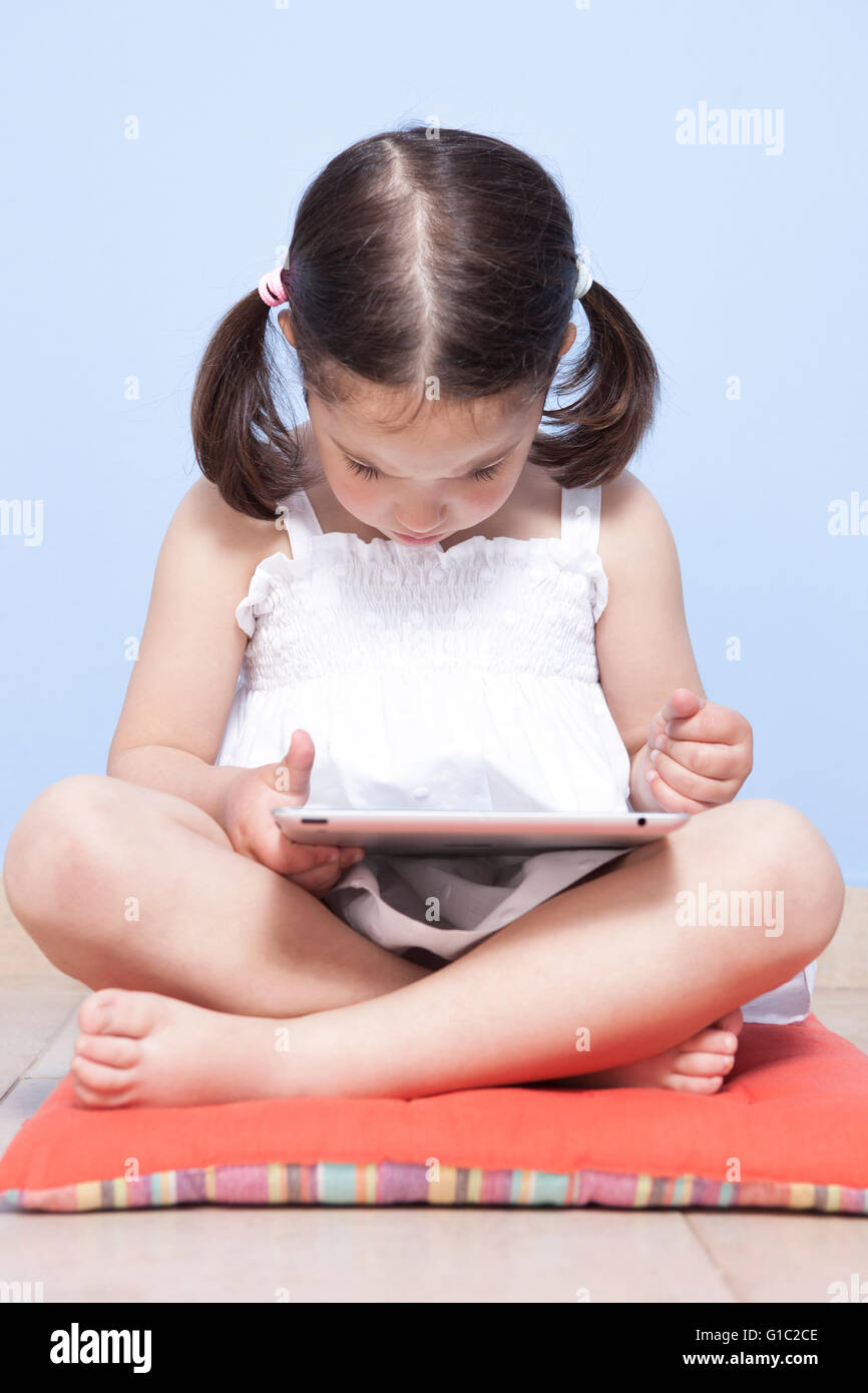 Little girl sitting in her room floor using tablet computer Stock Photo ...