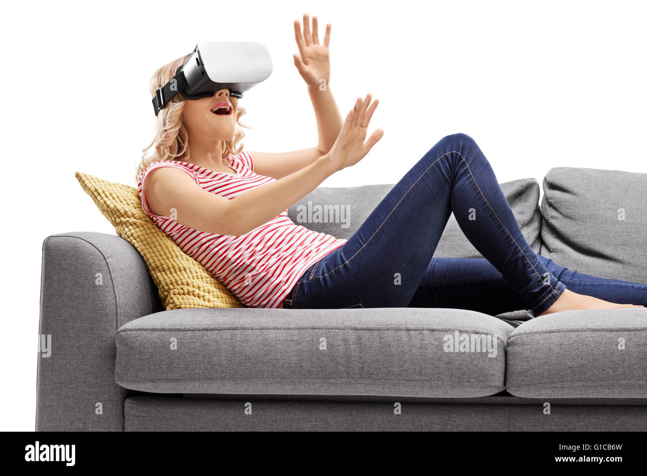Joyful woman experiencing virtual reality seated on a gray sofa ...