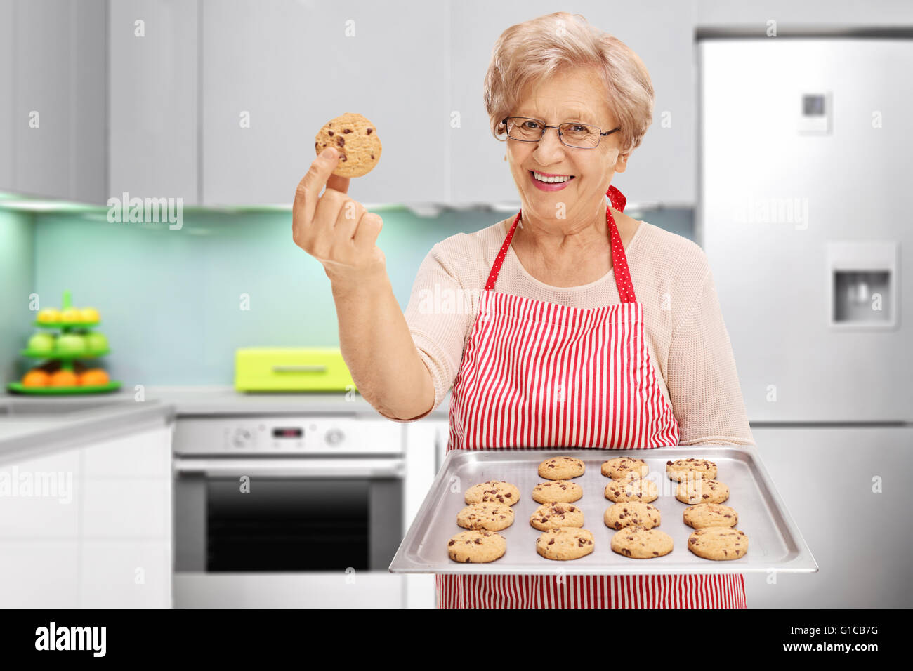 Senior lady showing her homemade chocolate chip cookies in a kitchen ...