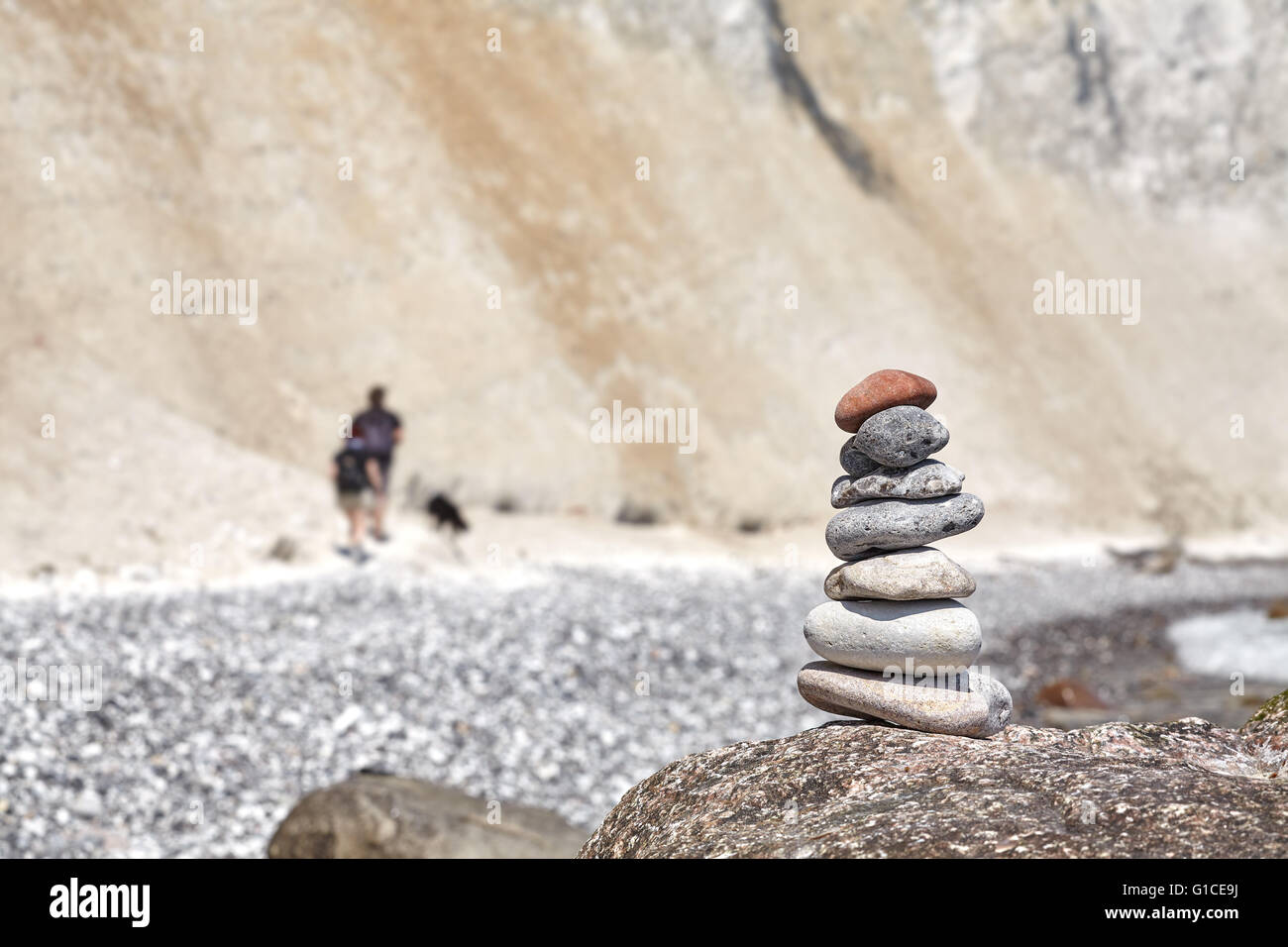 Stack of stones and blurred walking people with dog in distance Stock ...