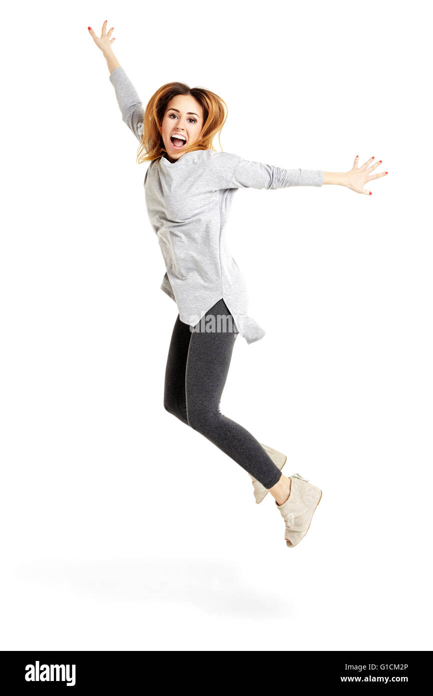 Full length shot of a young woman jumping and looking at you. Isolated ...