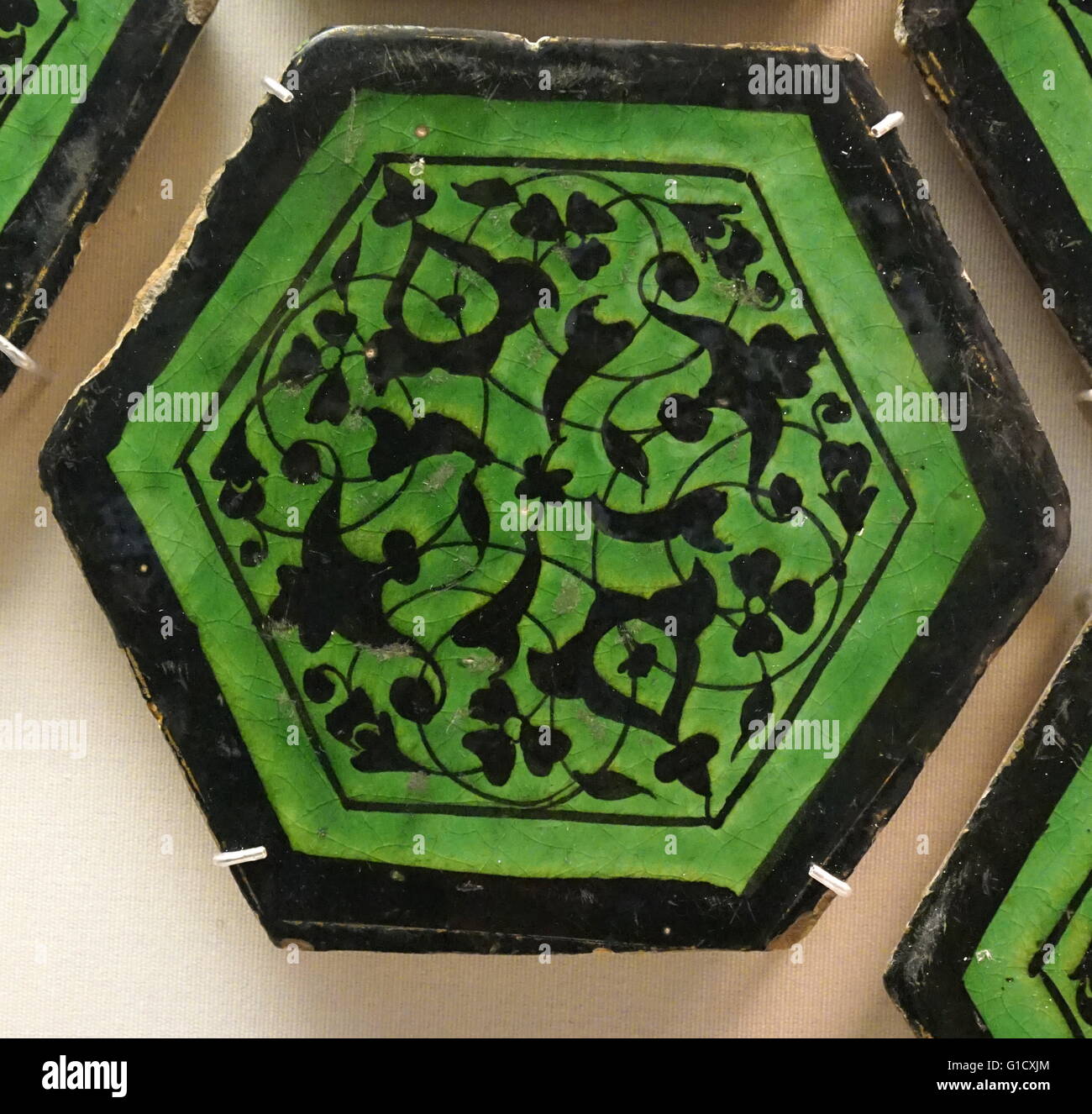 Hexagonal tiles painted with black cruciform arabesque scrolls and ...