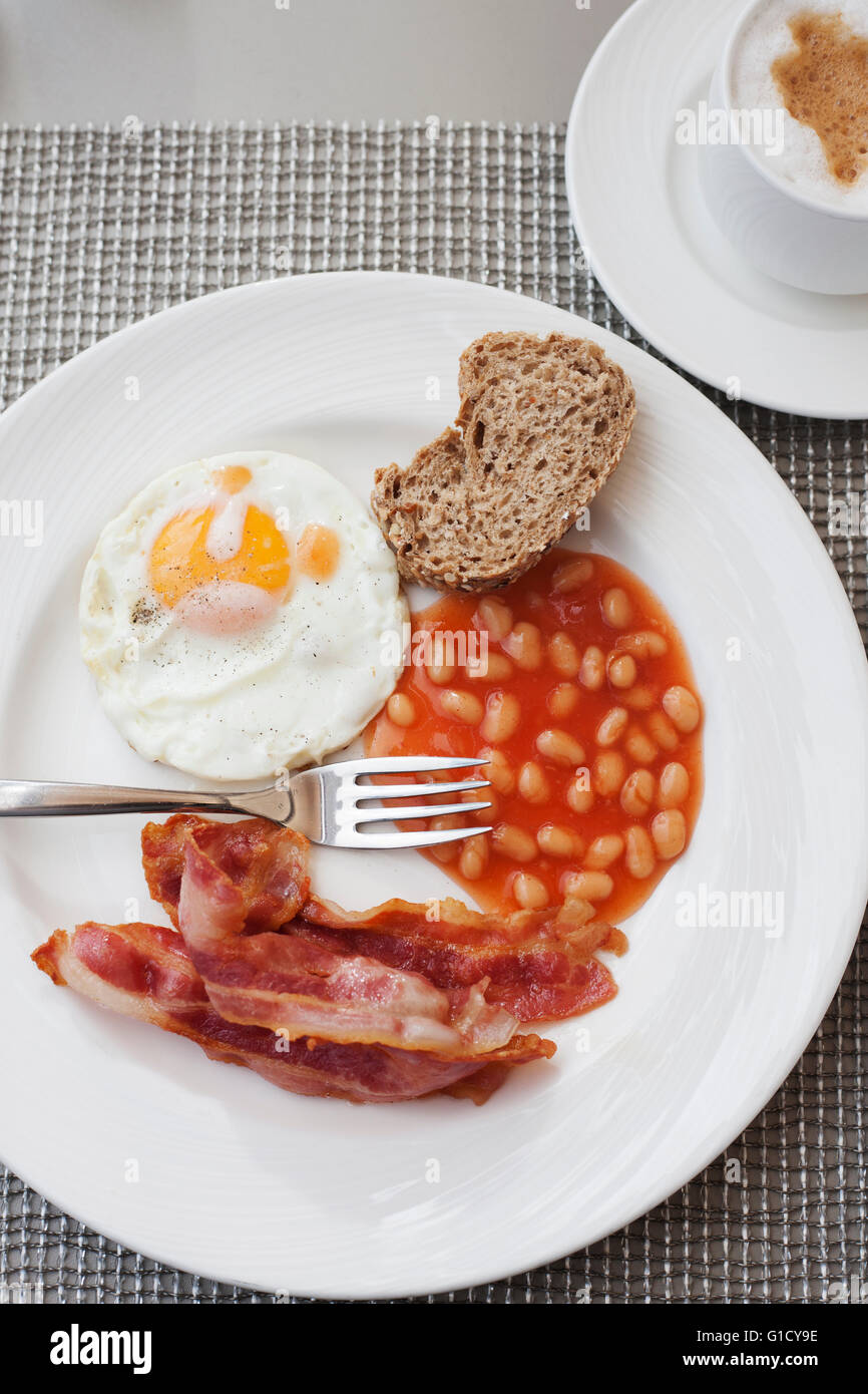 Plate of English fried breakfast consisting of fried egg, baked beans ...