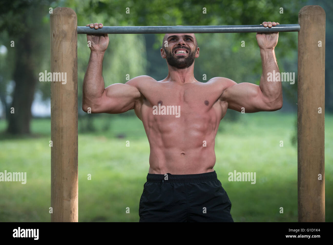 Muscular Built Young Athlete Working Out In An Outdoor Gym - Doing Chin ...