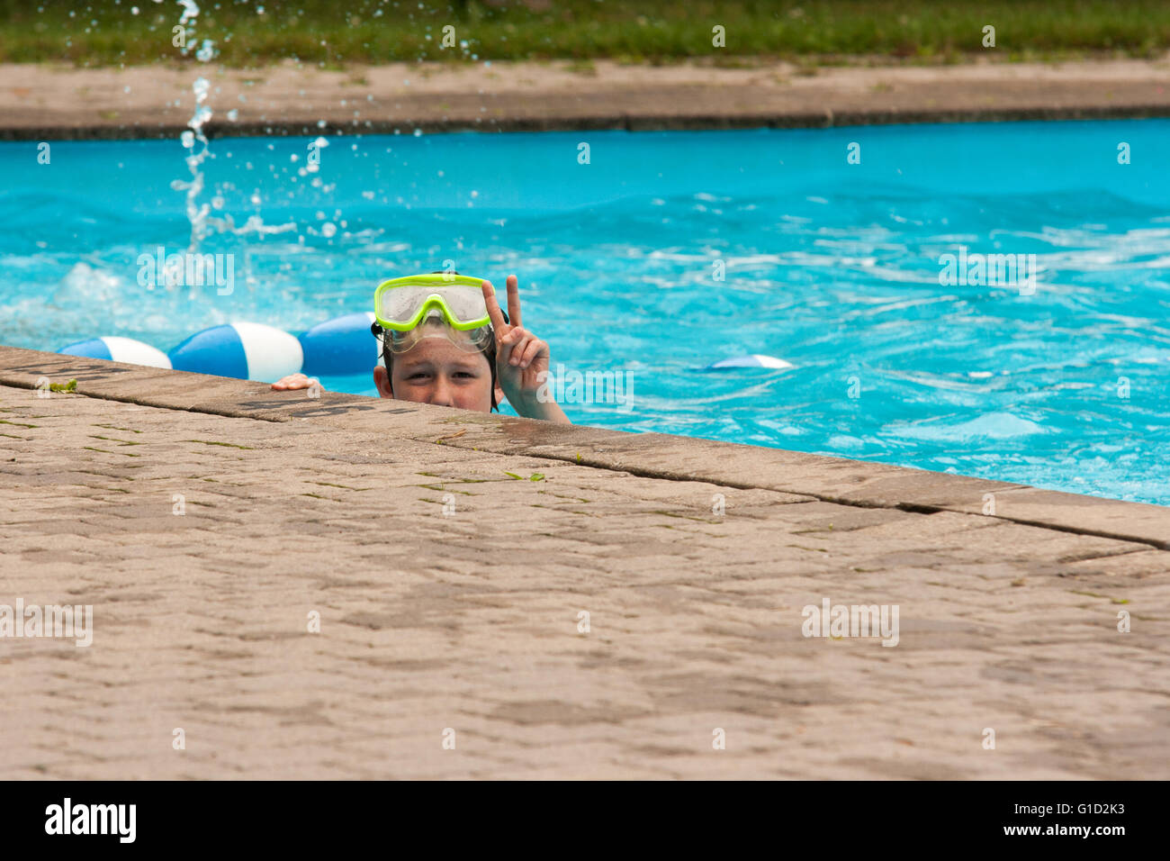 Young boy in pool displaying the hand gesture for peace Stock Photo - Alamy