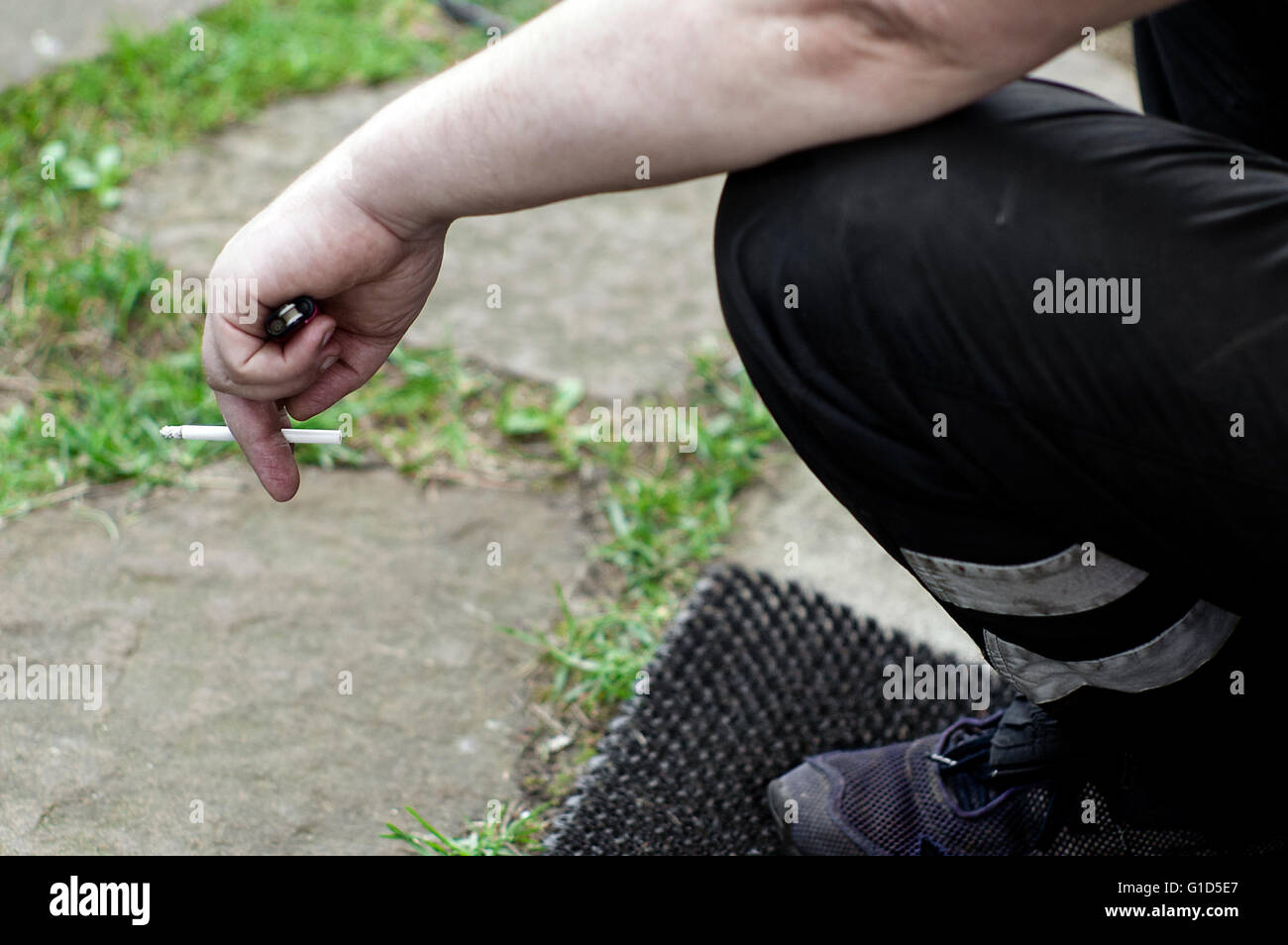 Worker having a cigarette break, sitting outdoors. Cropped shot with ...