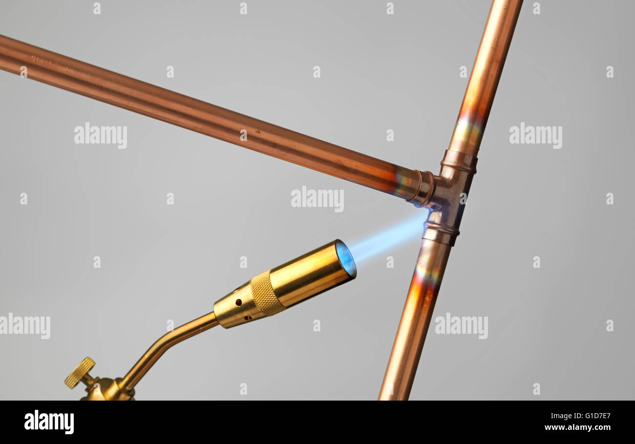 Blowtorch with flame on gray with copper pipe Stock Photo - Alamy