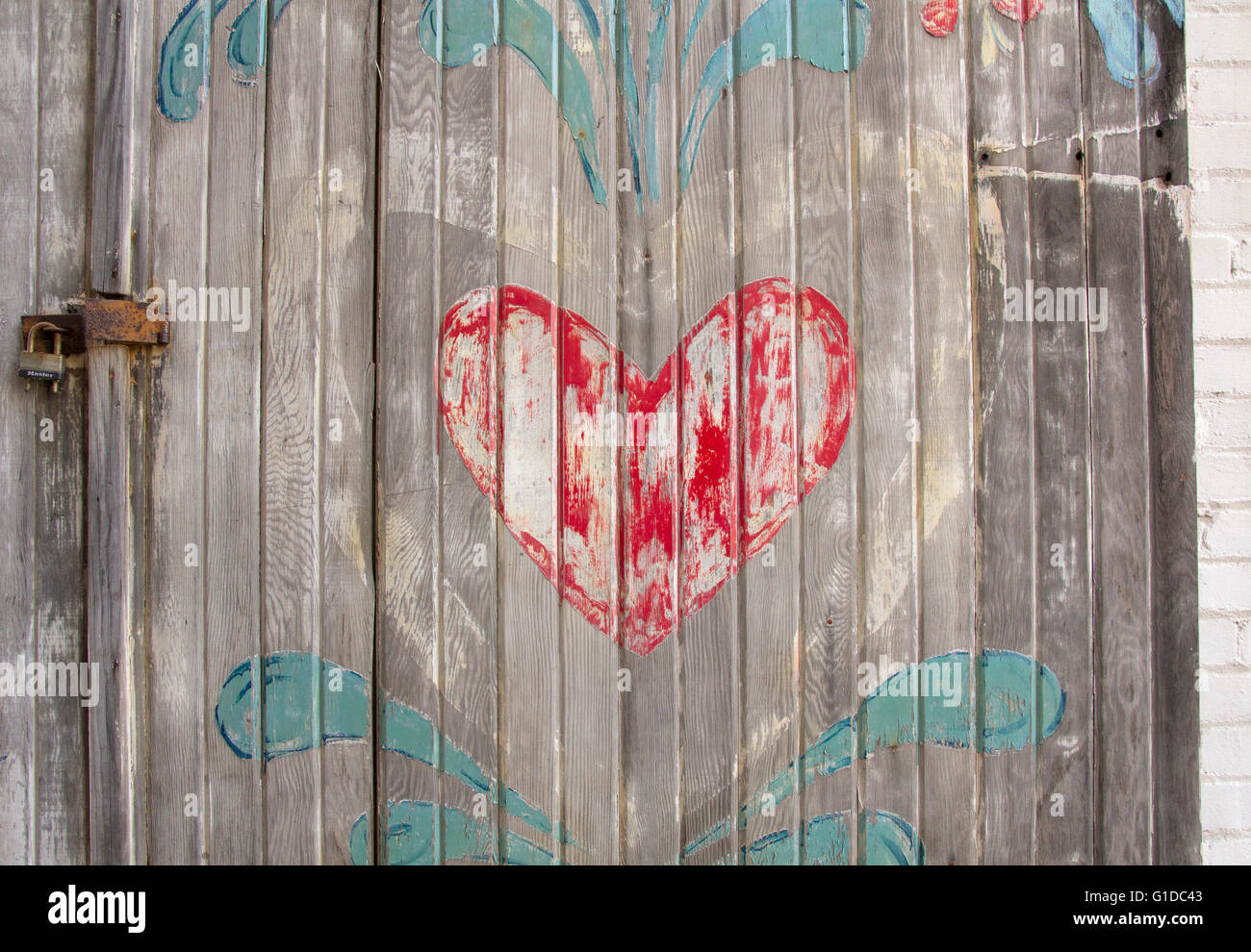 Faded red heart with chipped paint on old wooden door with lock Stock ...