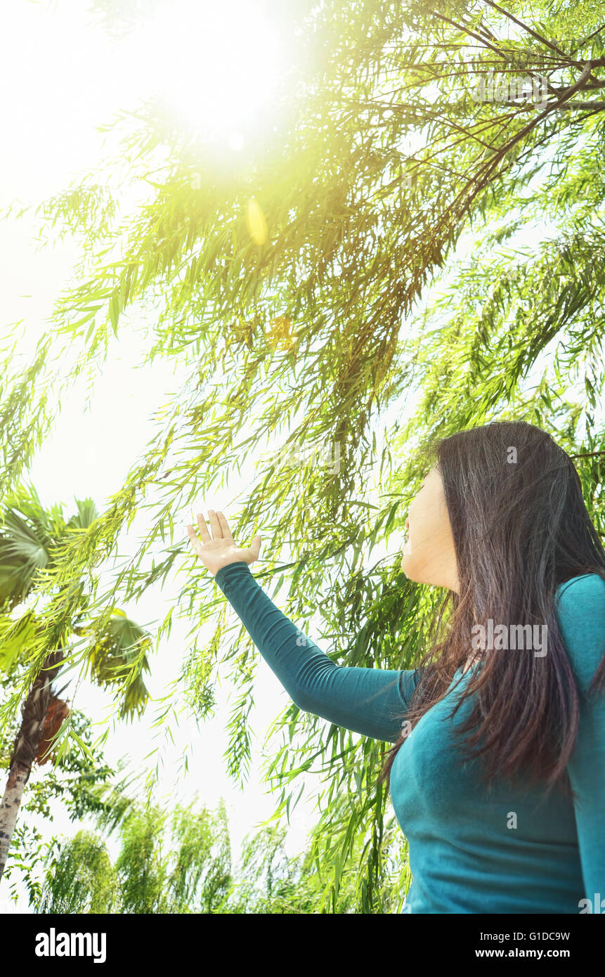 Girl rising her hand to touch leaves Stock Photo - Alamy