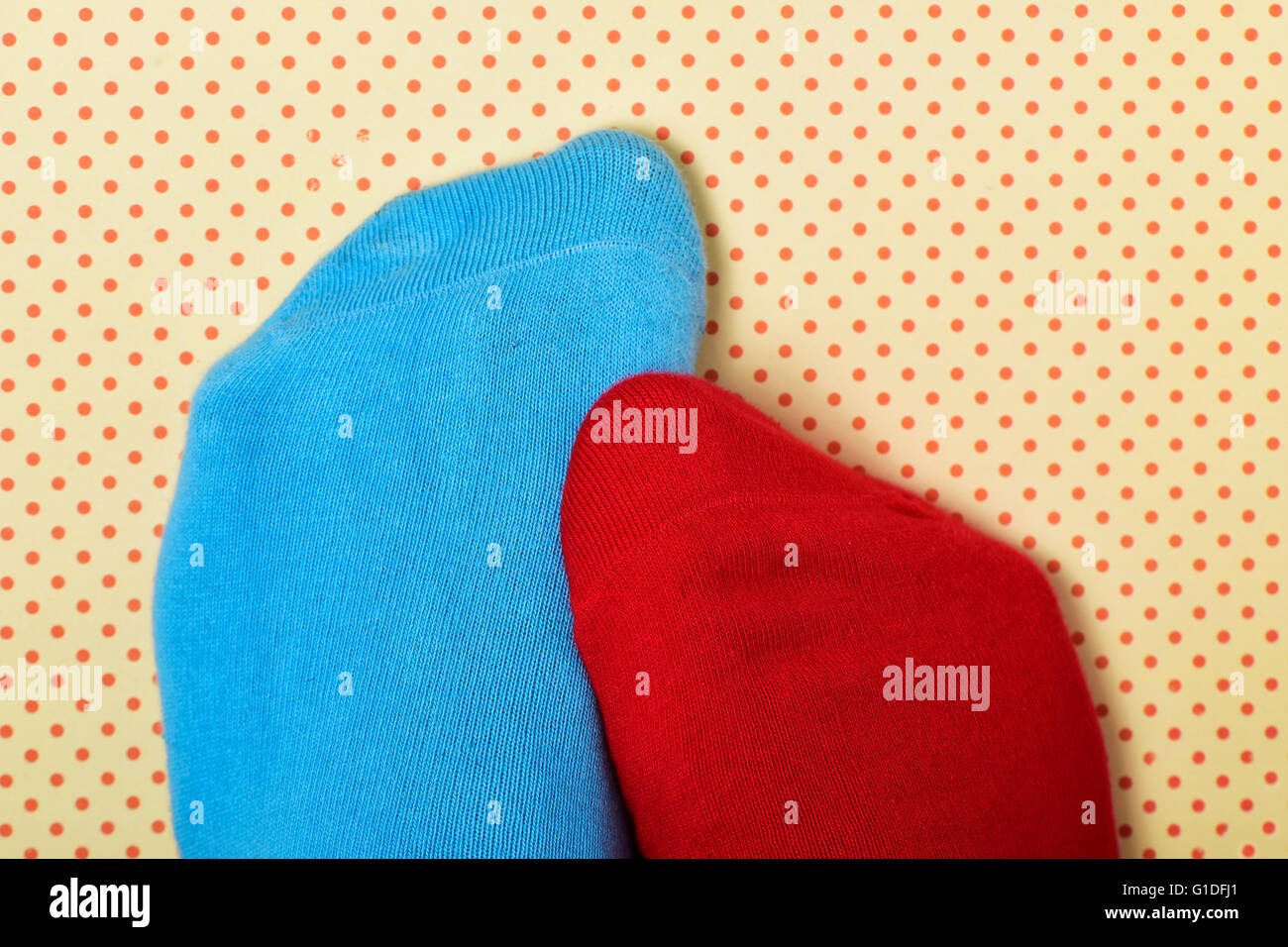 closeup of the feet of someone with a blue sock in one foot and a red ...