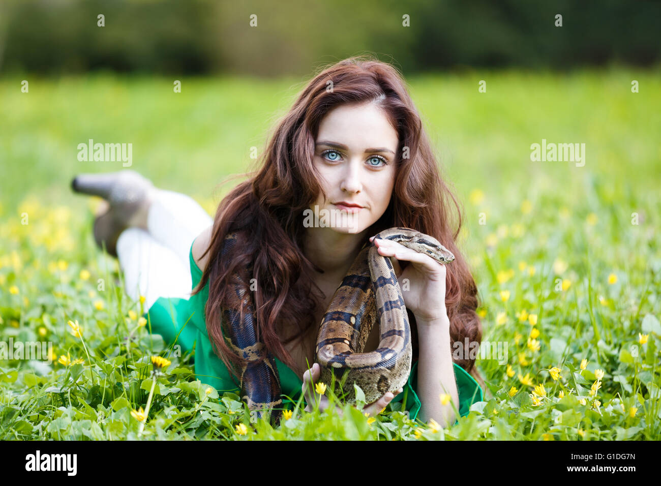 Happy smiling teenage girl lying on the green grass with python Stock ...