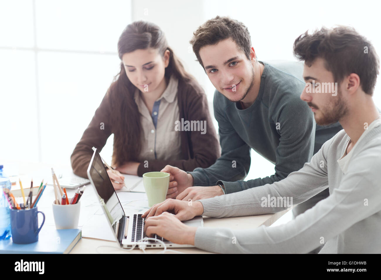 Group of college students at desk using a laptop, networking and ...