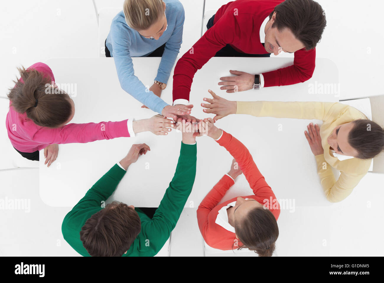 Business people sitting around the table stacking hands one over each ...