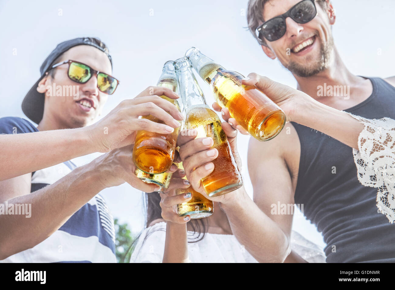Happy smiling friends clinking bottles of beer outdoors Stock Photo - Alamy