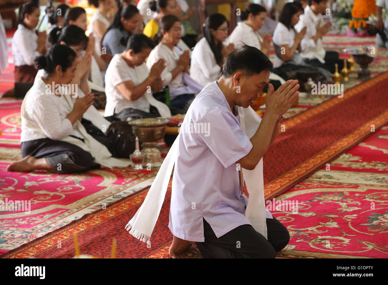 Wat Ong Teu buddhist temple. Seated man chanting and reading prayers at ...