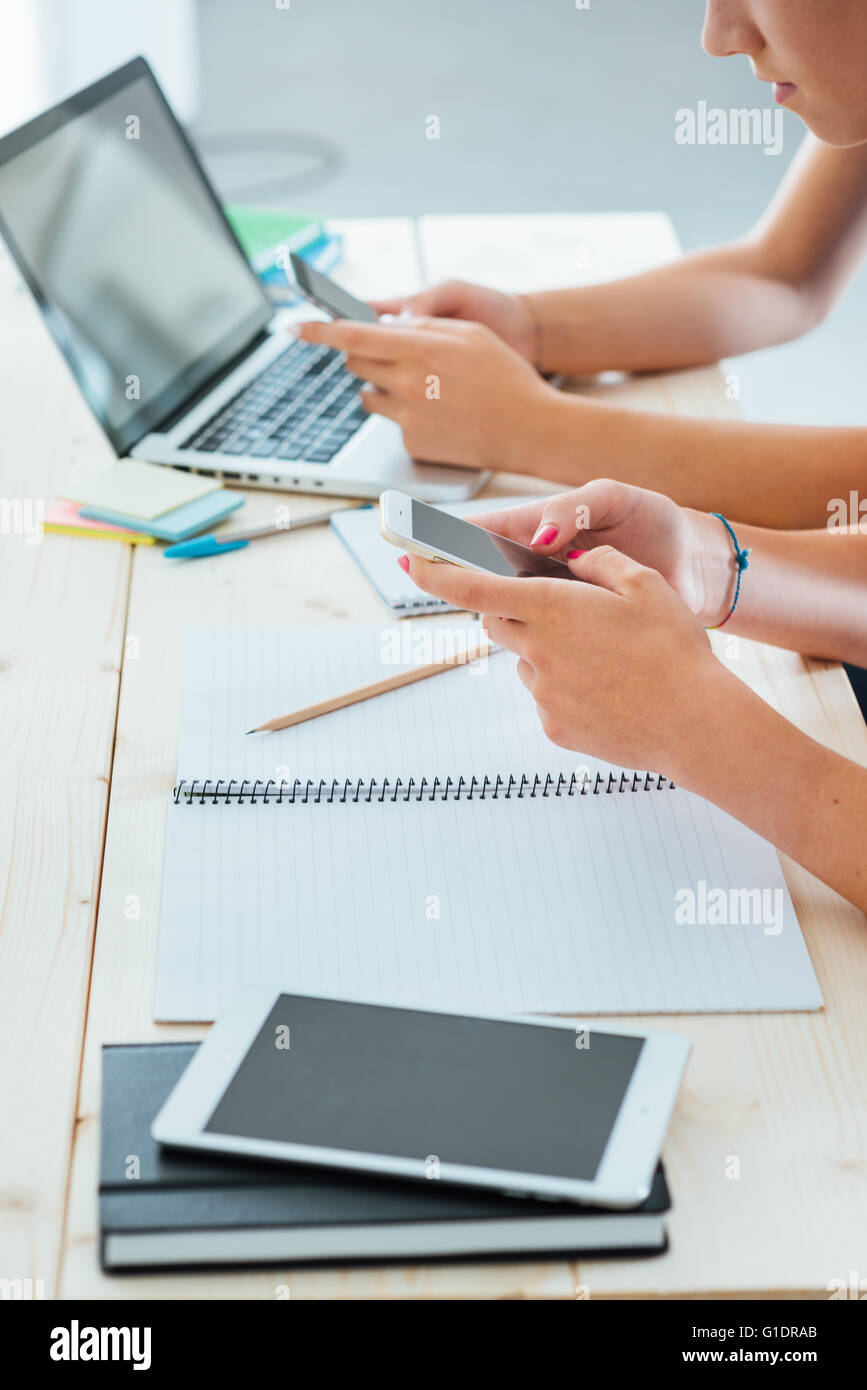 Teenager female students sitting at desk, studying and using touch ...