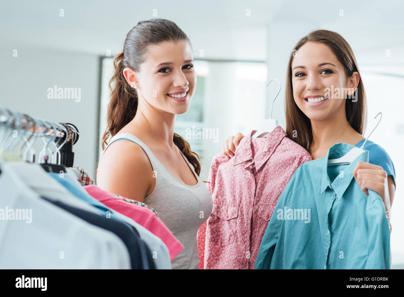Teenagers shopping women's clothing at the store and smiling at camera ...