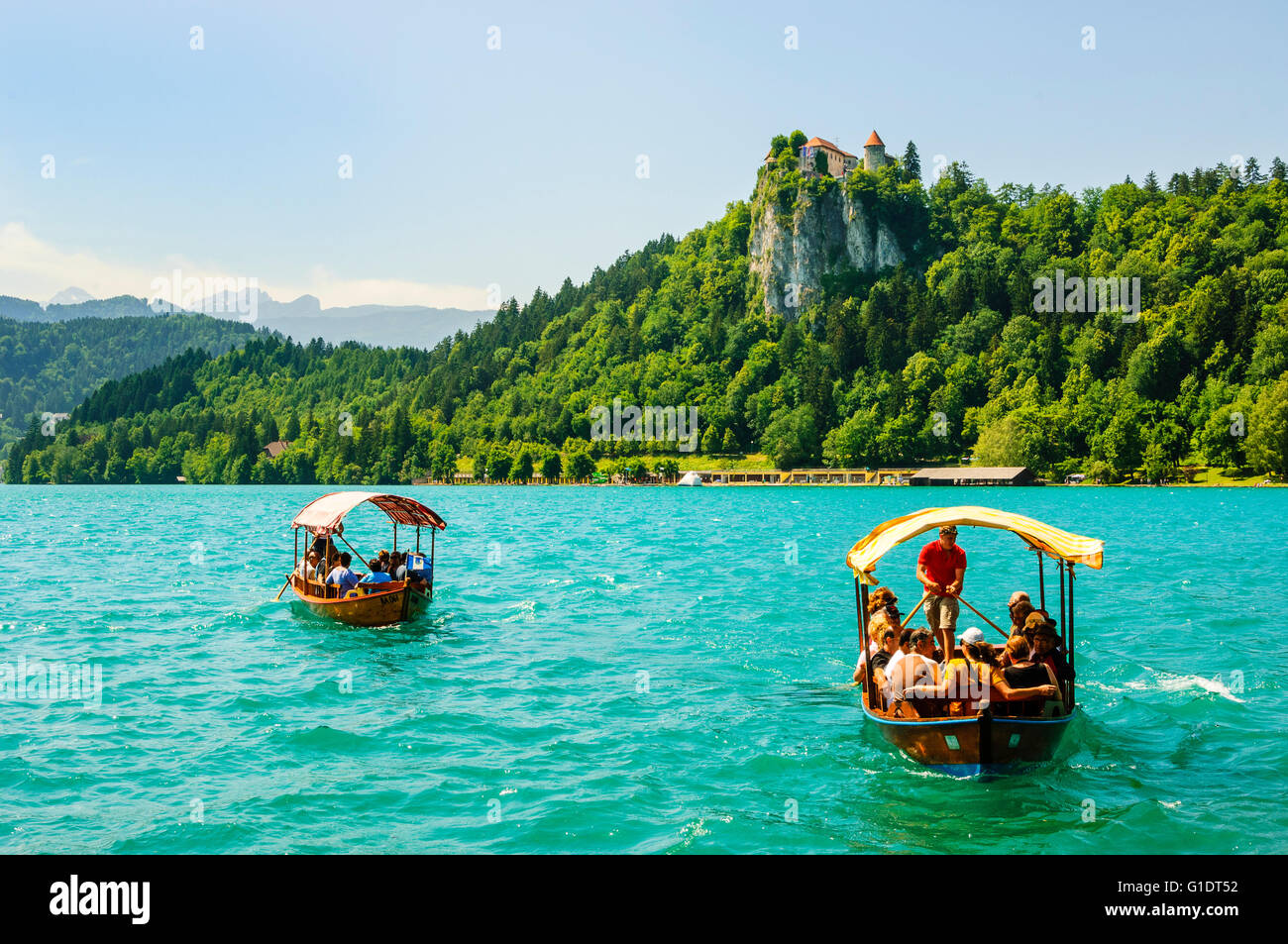 Tourists ride on traditional wooden pletna, Lake Bled, Slovenia, with ...