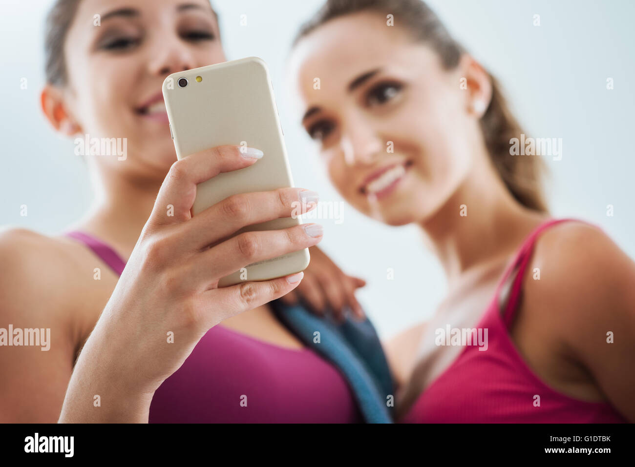 Happy young girls at the gym using a fitness app on a smart phone ...