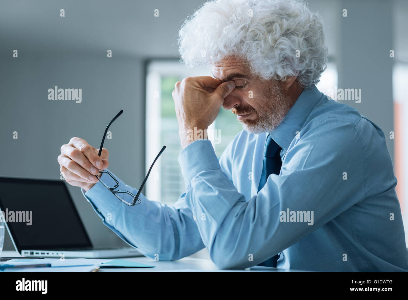 Stressed exhausted businessman sitting at office desk, failure and loss ...