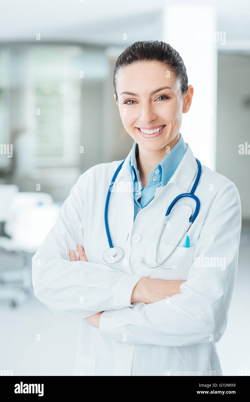 Confident female doctor posing in her office and smiling at camera ... Confident female doctor posing in her office and smiling at camera ...