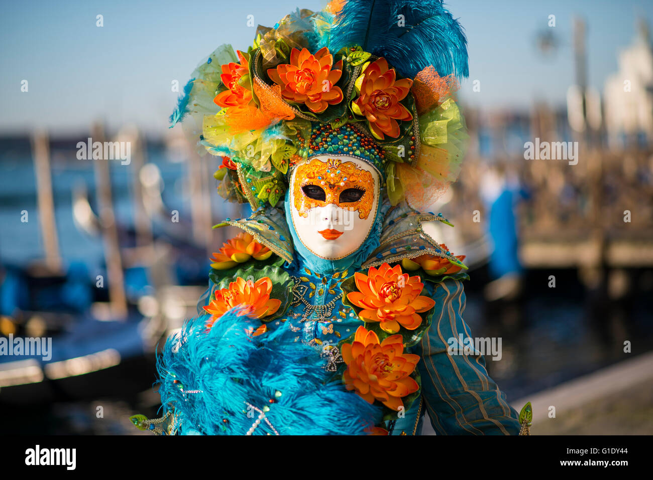Costumed Venetian woman standing in front of the gondolas in St. Mark's ...