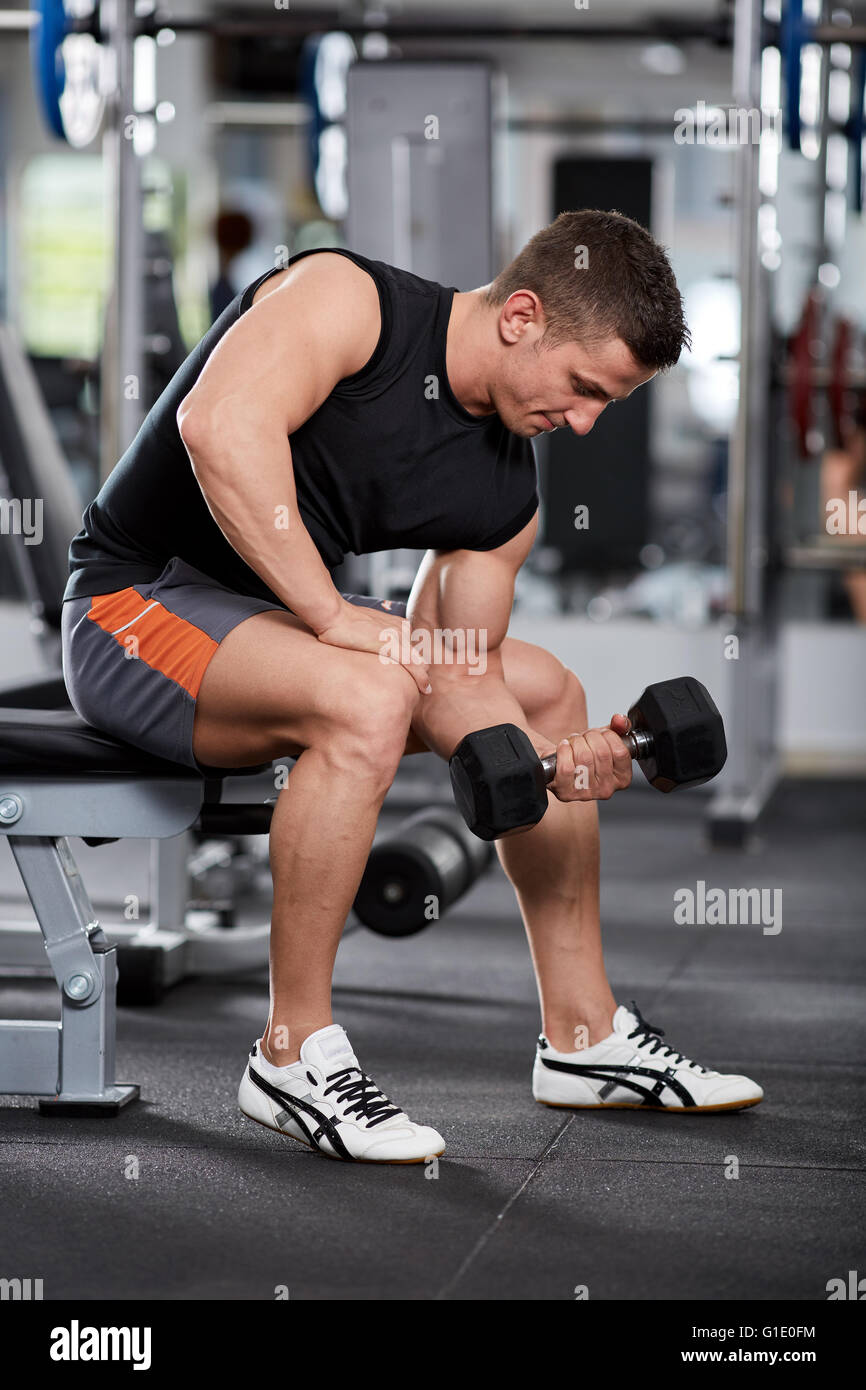 Athletic man doing biceps curl in seated position in the gym Stock ...
