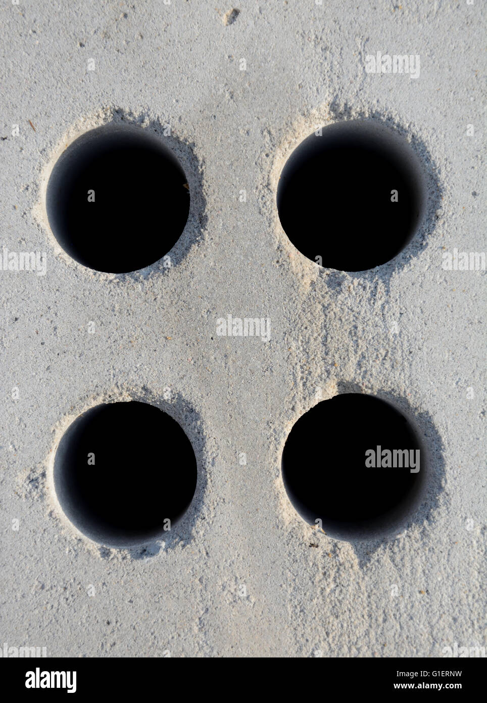 Four round holes in grey concrete wall - background Stock Photo - Alamy