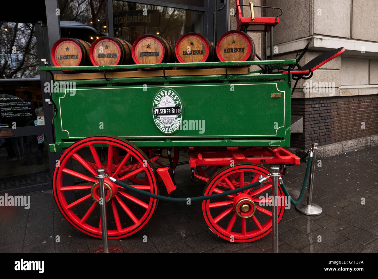A cart with some Heineken barrels on the pavement at the entrance of ...