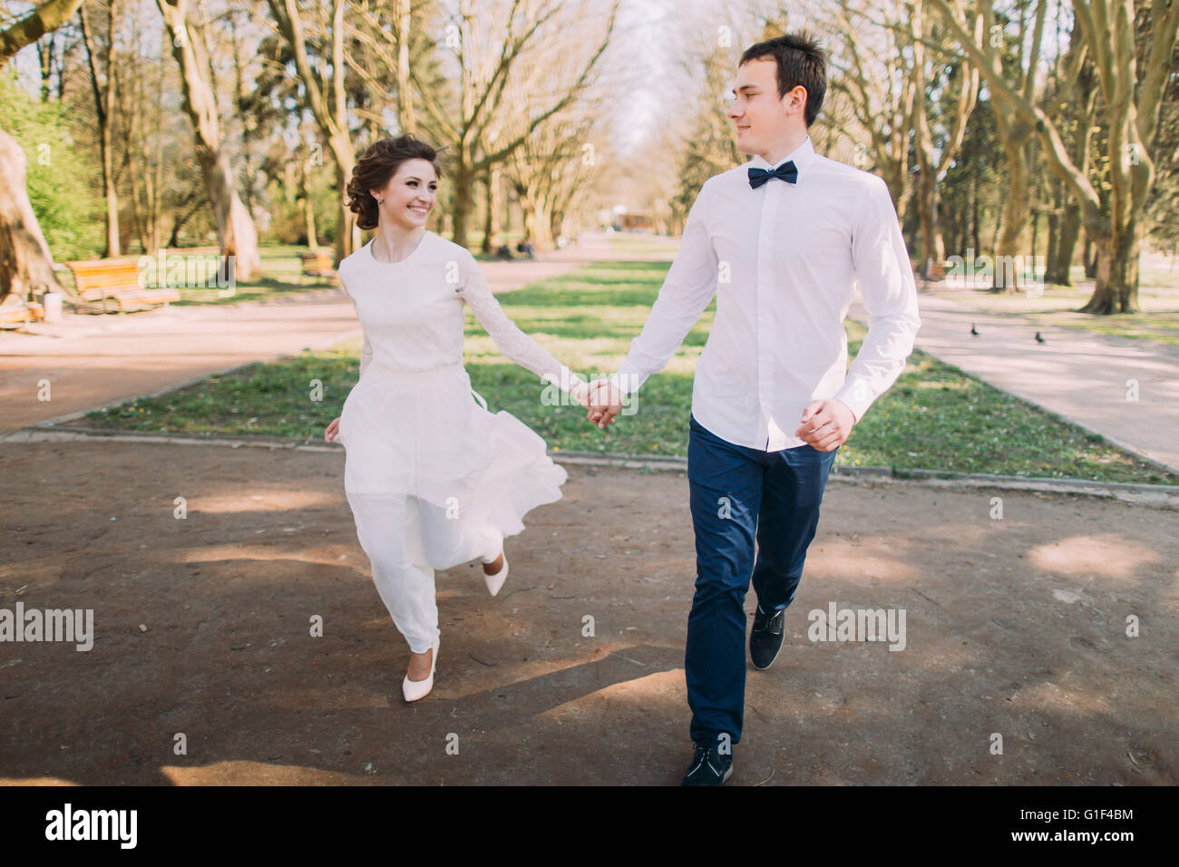 Happy wedding couple charming groom and blonde bride running with ...