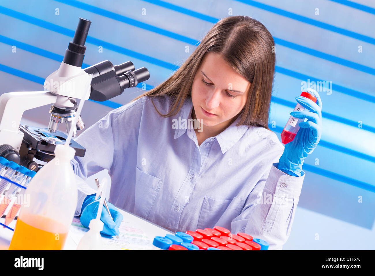 MODEL RELEASED. Female lab technician making notes in the laboratory ...