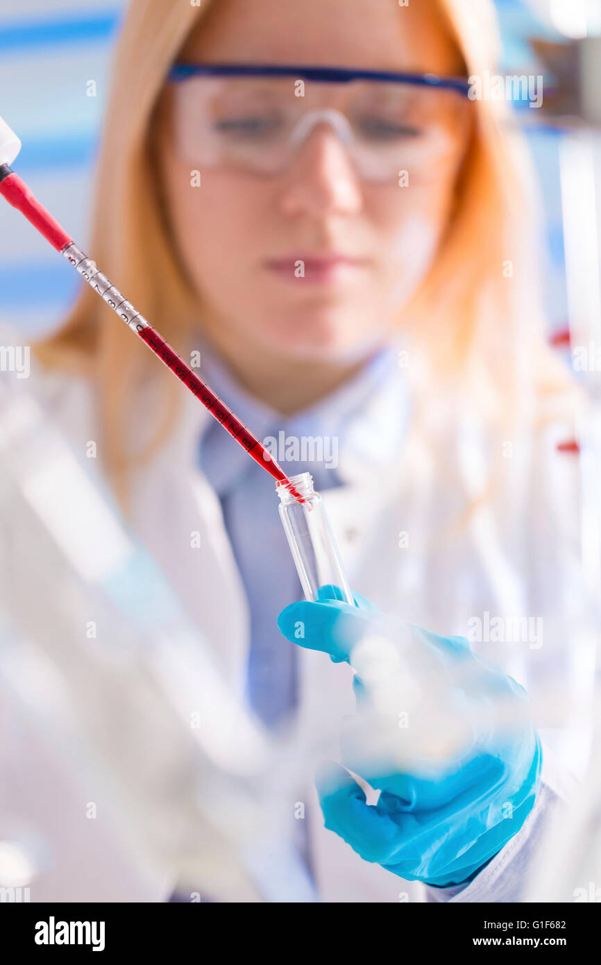 MODEL RELEASED. Female lab technician dripping chemical into test tube ...
