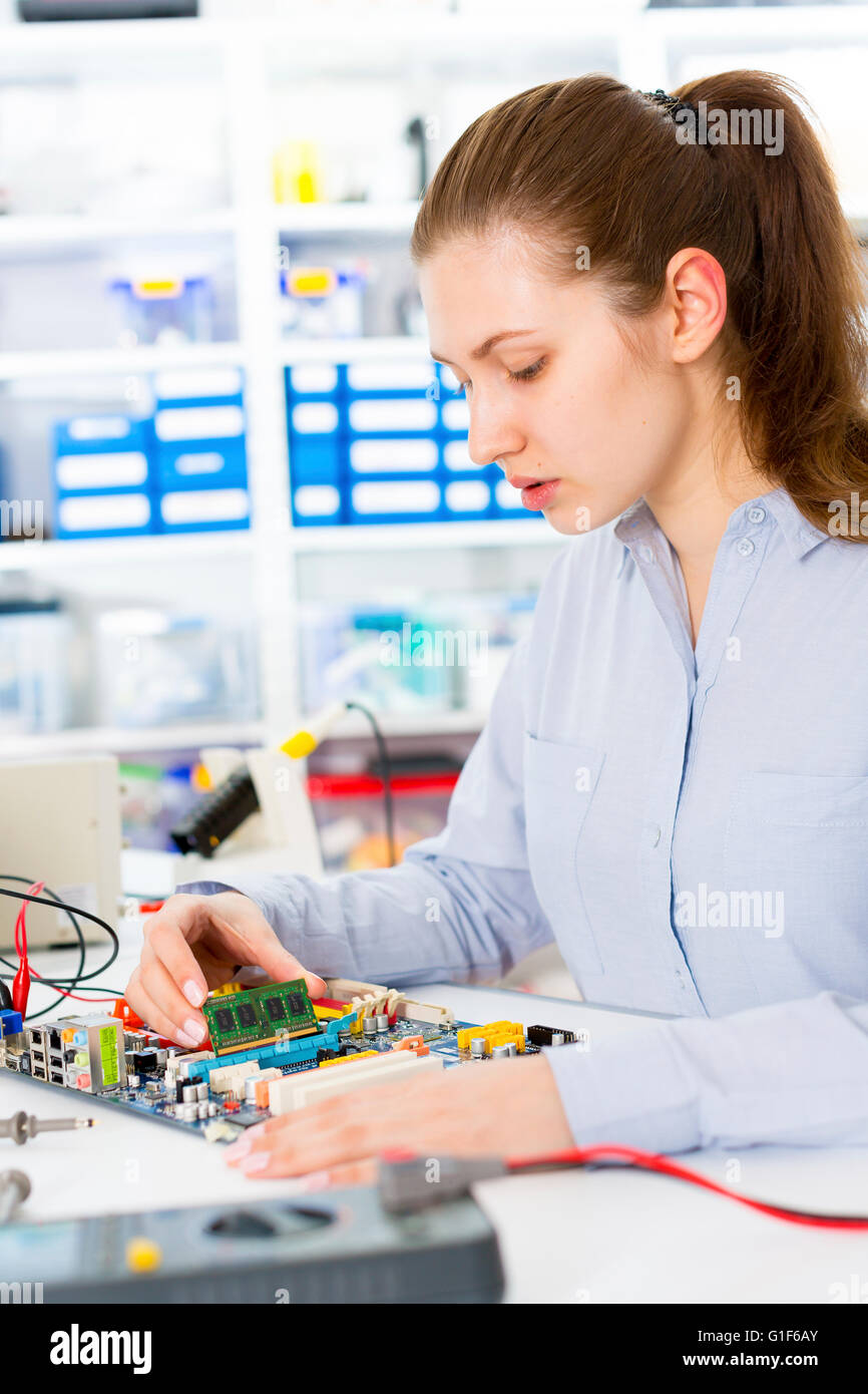 MODEL RELEASED. Female electrical engineer working on a circuit board ...