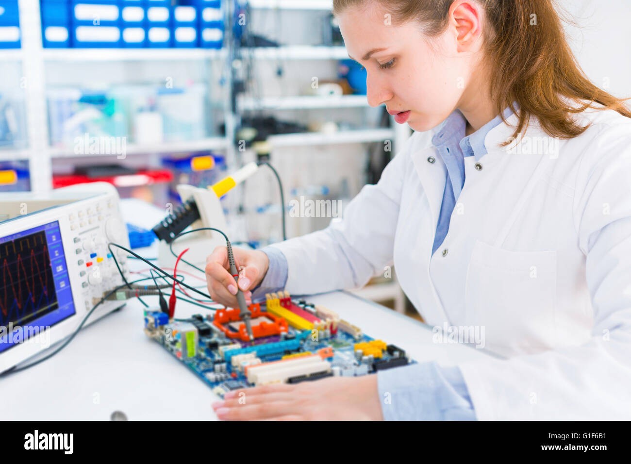 MODEL RELEASED. Female electrical engineer working on a circuit board ...