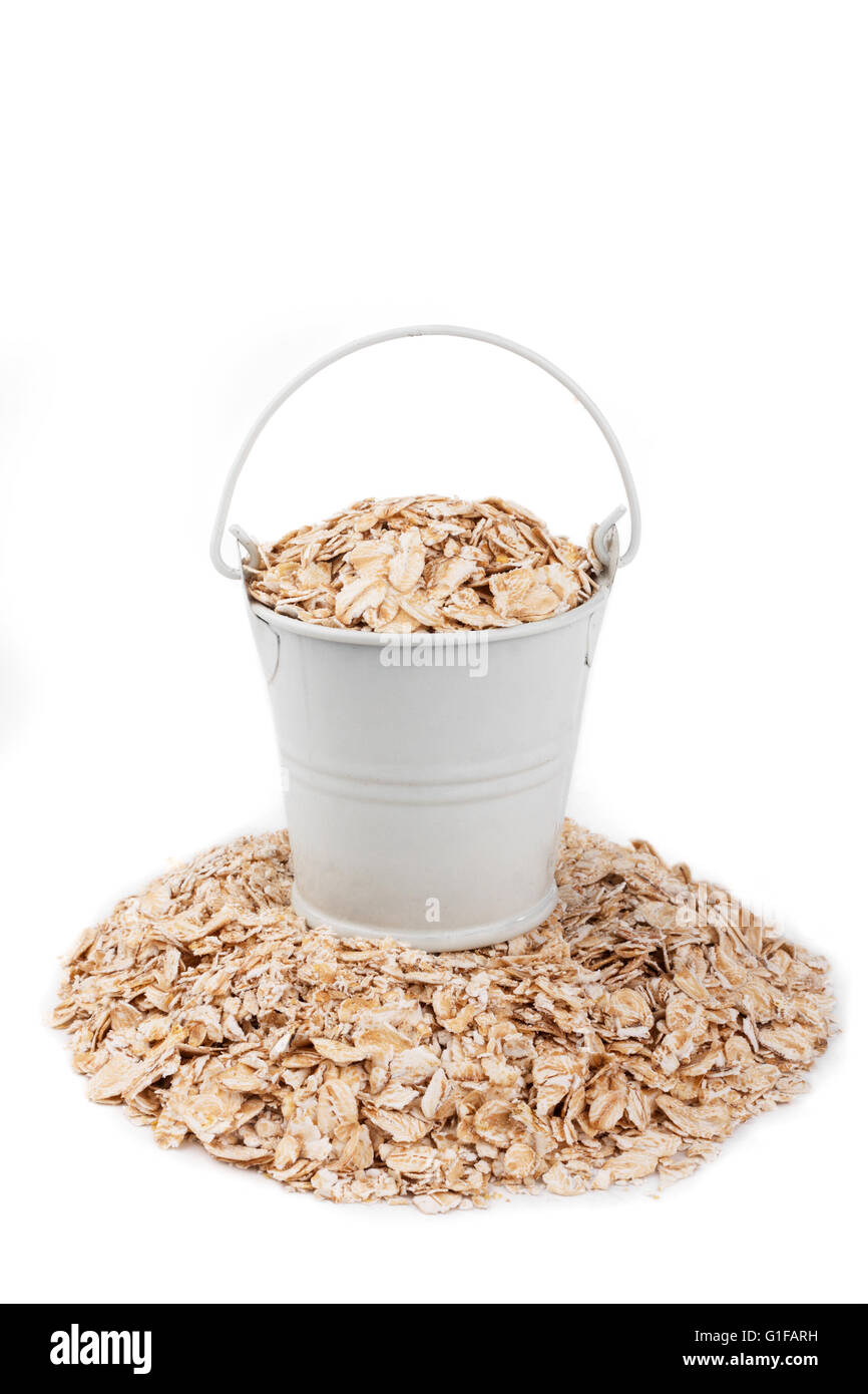 White bucket full of oat flakes, stands on a heap oat flakes, on a ...