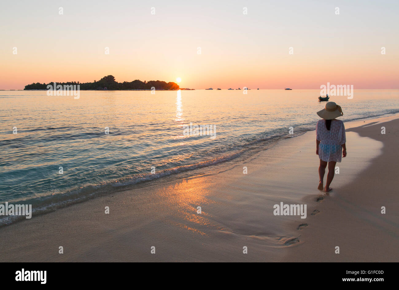 Woman on beach at sunset, Rasdhoo Island, Northern Ari Atoll, Maldives ...
