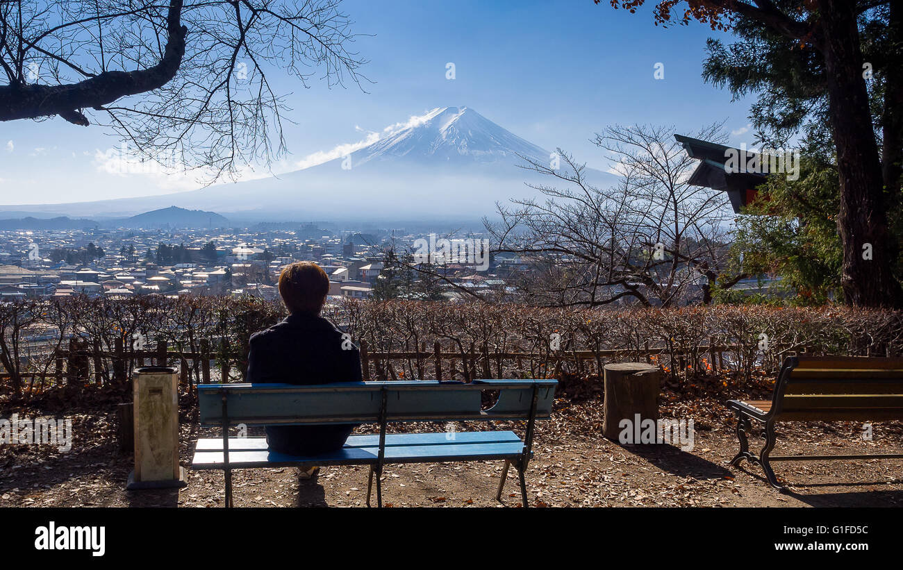 A man sitting on a bench seeing Mt. Fuji with clear sky alone Stock ...