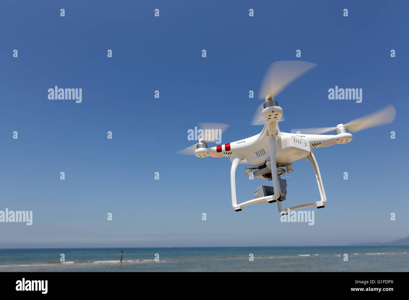 White drone quad copter with flying in the clear blue sky Stock Photo ...