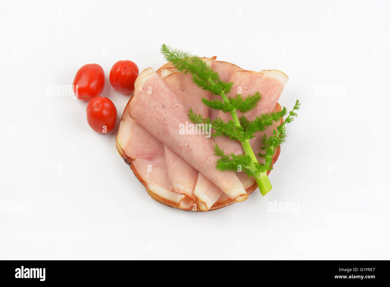 stack of ham slices with fresh dill and cherry tomatoes on white ...