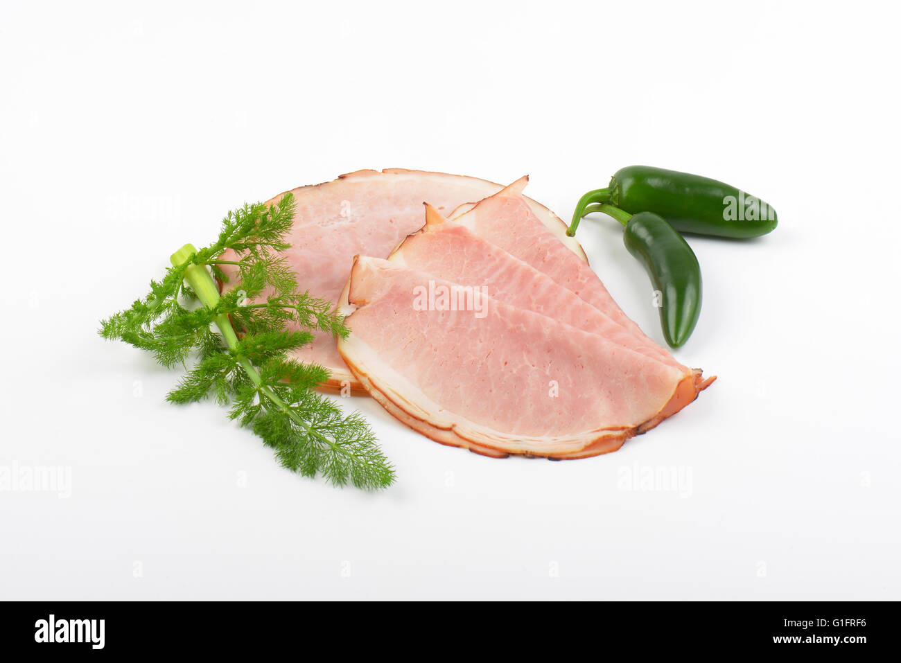 slices of ham with fresh dill and chili peppers on white background ...