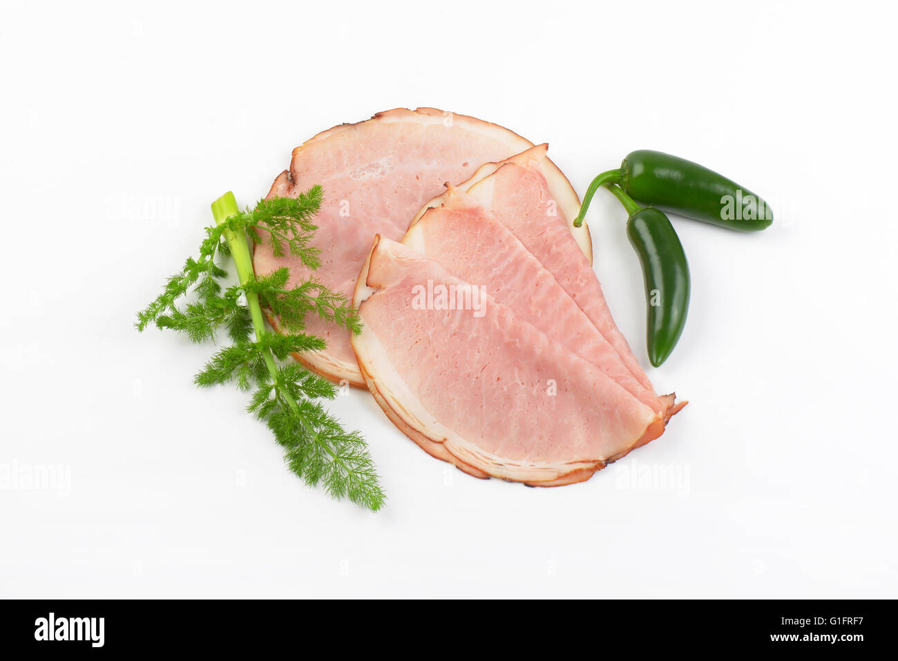 slices of ham with fresh dill and chili peppers on white background ...