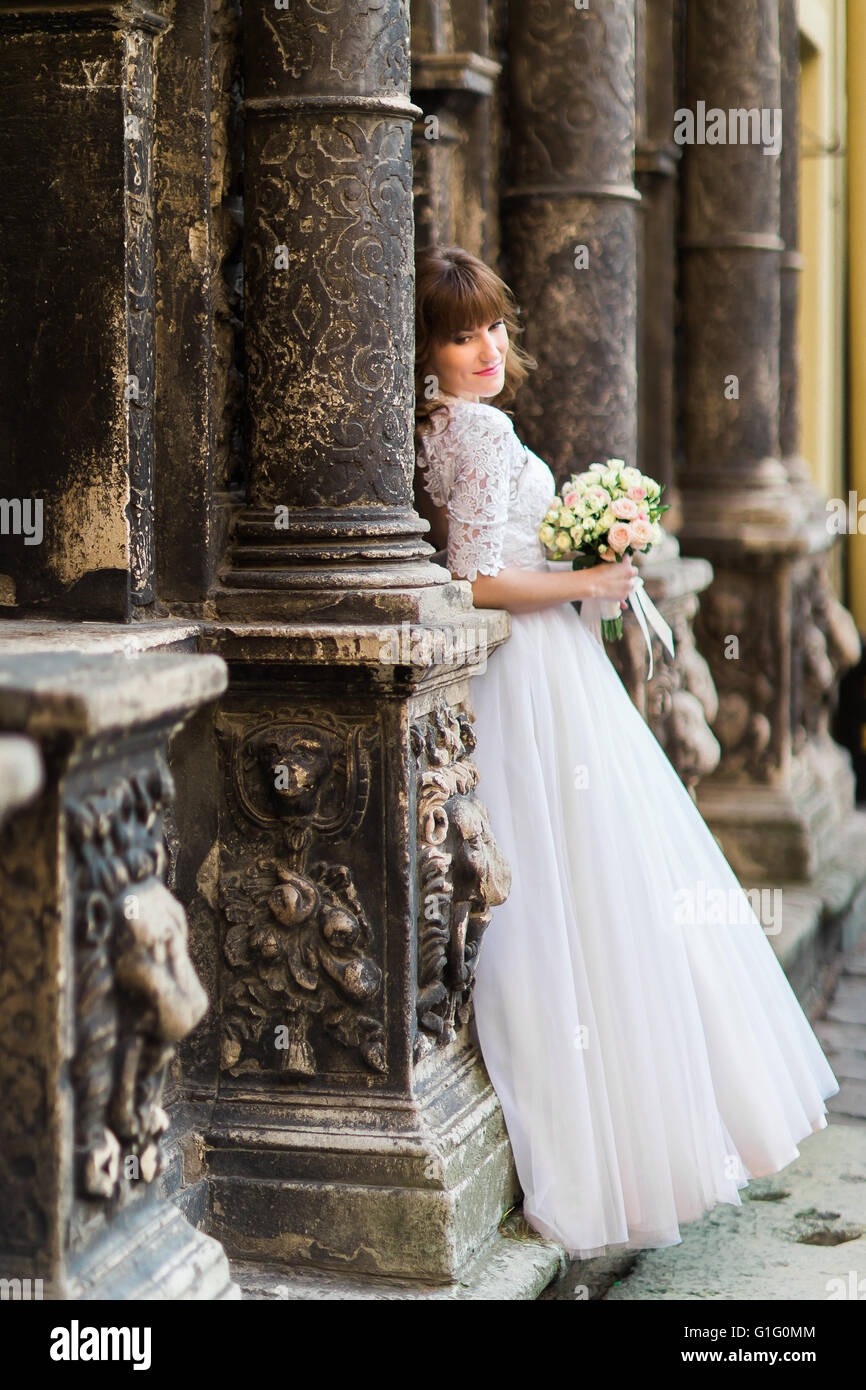 Beautiful young bride looking towards between the columns of old ...