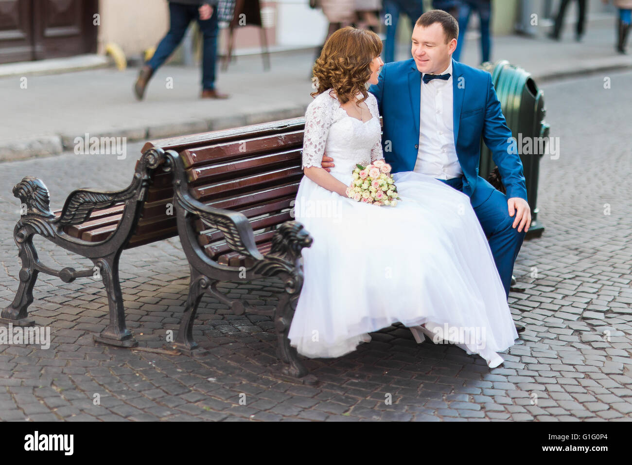 Elegant gorgeous happy bride and groom sitting on a bench Stock Photo ...