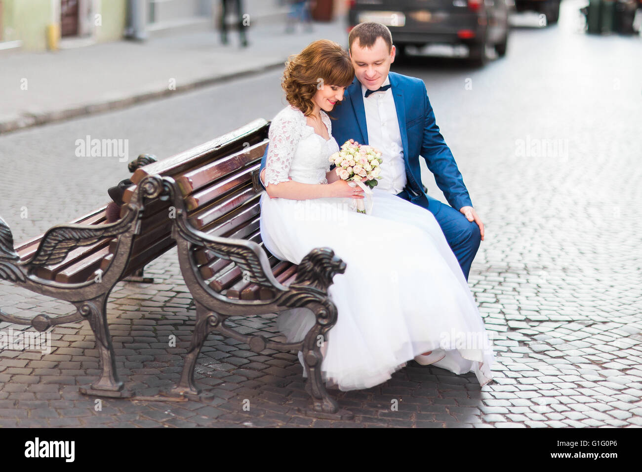 Elegant gorgeous happy bride and groom sitting on a bench Stock Photo ...