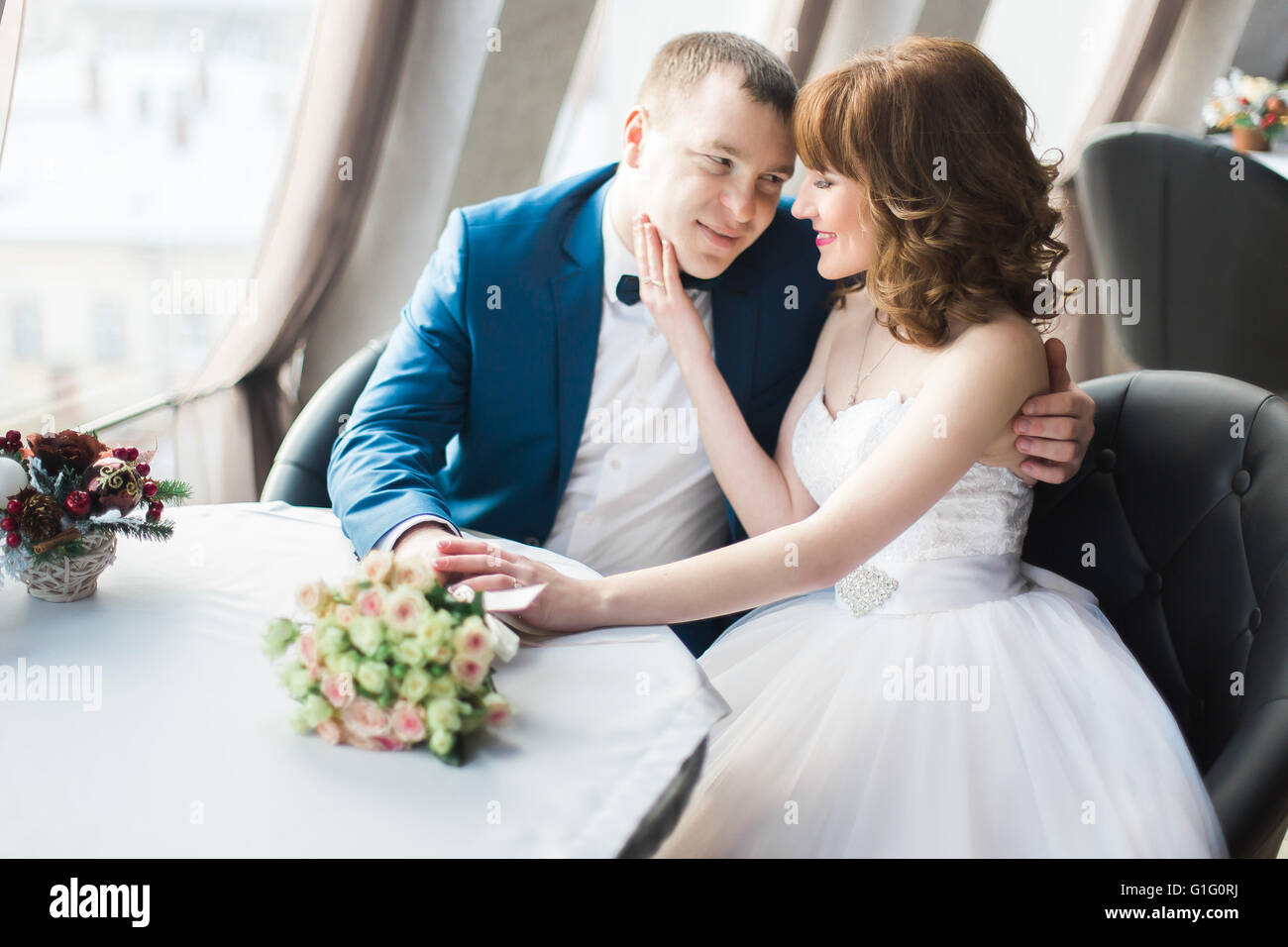 Gorgeous happy brown hair bride touching face of elegant groom in blue ...